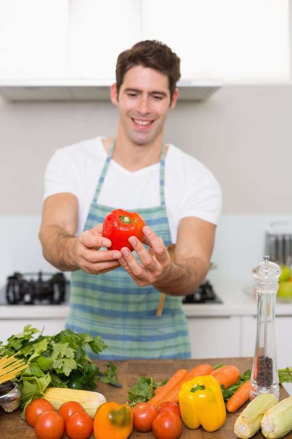 Smiling Man Holding Out Bell Pepper with Vegetables in Kitchen Stock ...