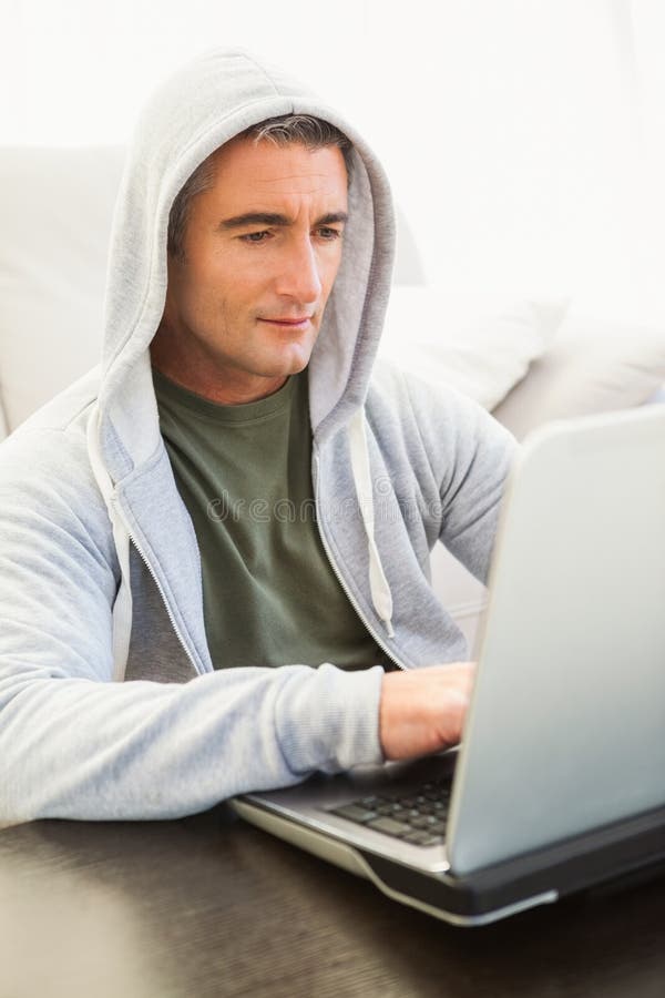 Smiling Man in Hood Jacket Using Laptop Stock Photo - Image of domestic ...