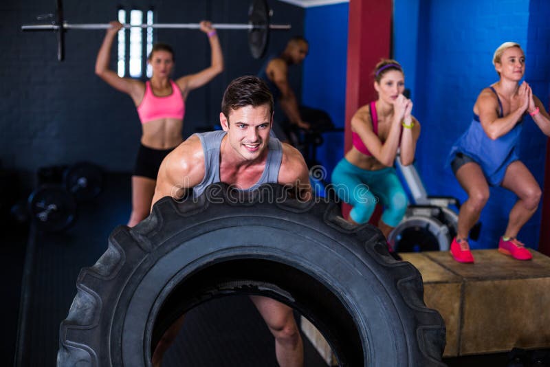 Smiling Man Lifting Tire in Gym Stock Photo - Image of care, physical ...