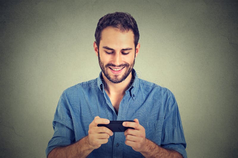 Smiling Man Looking At His Smart Phone While Text Messaging Or Watching