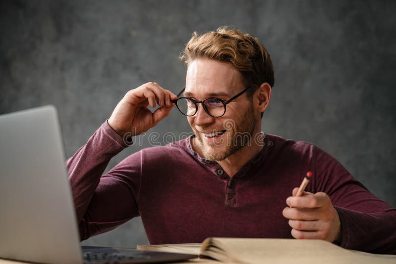 The Smiling Man Looking into Laptop Screen while Sitting at Table in ...