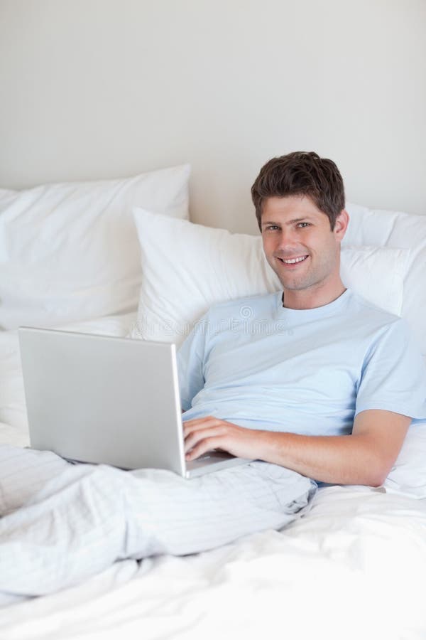 Smiling Man Lying in Bed with Notebook Stock Photo - Image of handsome ...