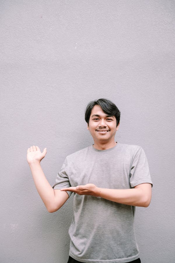 Smiling Man Presenting Product with Open Hand on Neutral Gray Backdrop ...
