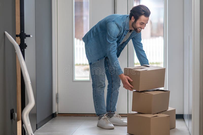 Smiling Man Standing Bent Over Stacking Boxes Stock Photo - Image of ...
