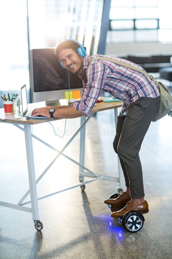 Smiling Man Standing on Hoverboard and Using Laptop in Office Stock ...