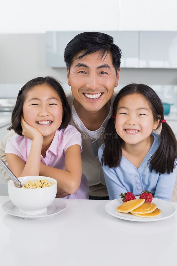 Smiling Man with Two Daughters Having Breakfast in Kitchen Stock Photo ...