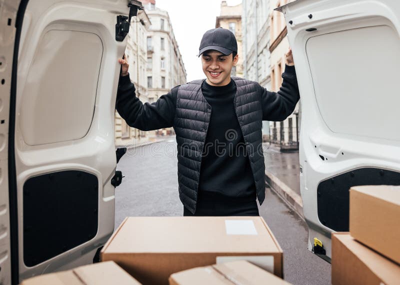 Smiling Man in Uniform and Cap Looking at Cardboard Boxes while ...