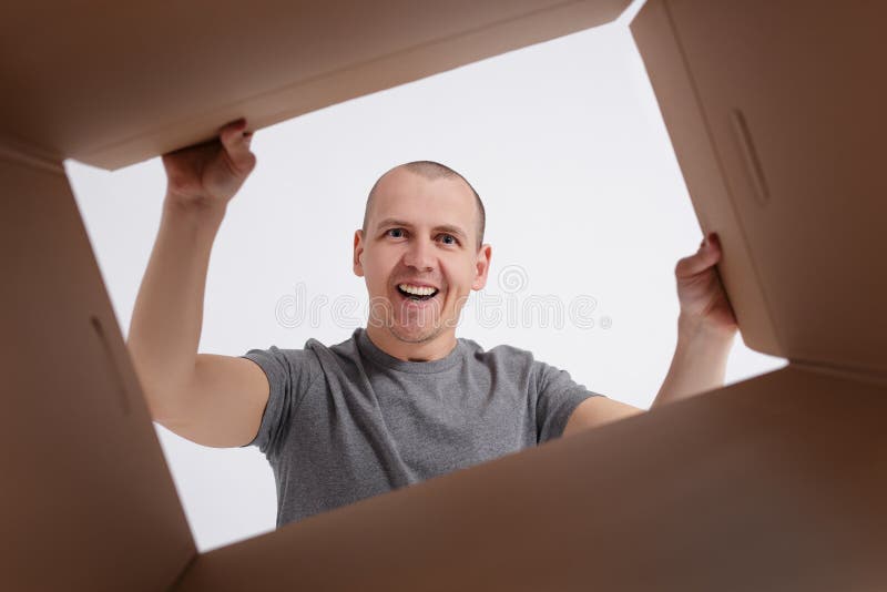 Smiling Man Unpacking and Opening a Carton Gift Box and Looking Inside ...