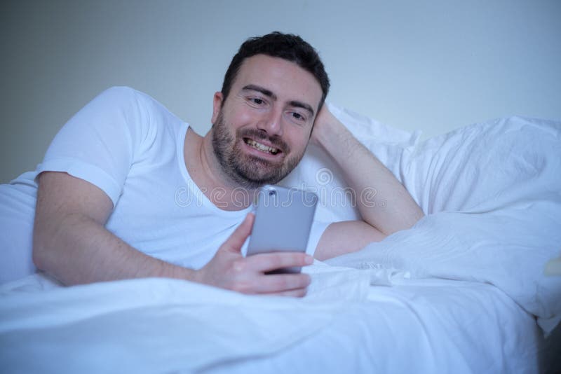Smiling Man Using His Smart-phone Lying in Bed Stock Image - Image of ...
