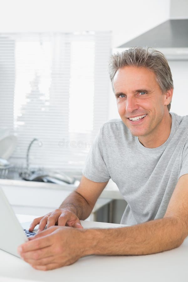 Smiling Man Using Laptop in Kitchen Stock Photo - Image of abode ...