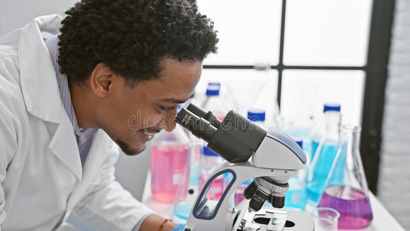 Smiling Man Using a Microscope in a Modern Laboratory Stock Photo ...