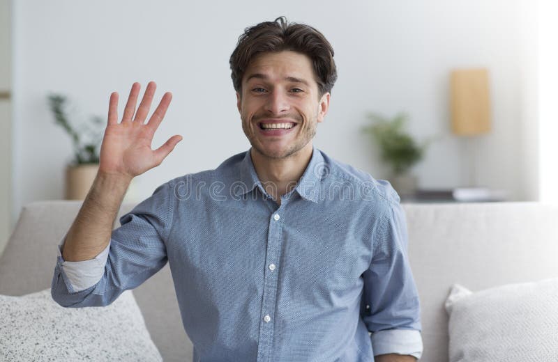 Smiling Man Waving Hand Sitting on Sofa Indoor Stock Photo - Image of ...