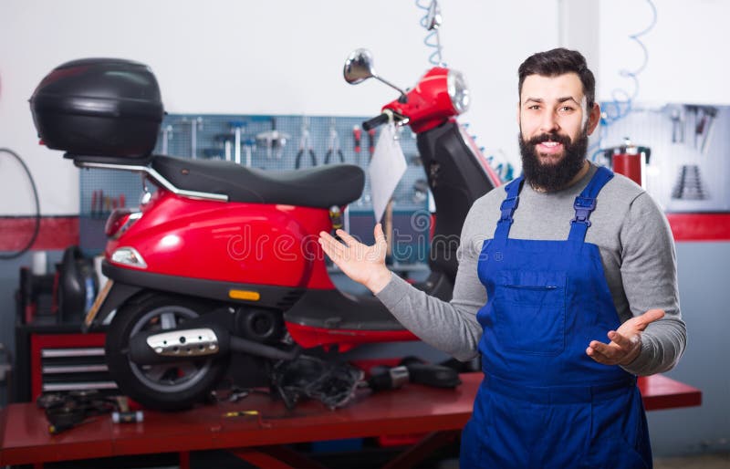 Smiling Man Worker Displaying His Workplace in Motorcycle Workshop ...