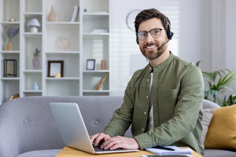 Smiling Man Working from Home with Laptop and Headset on a Video Call ...