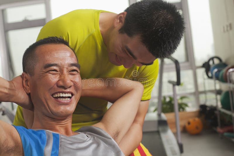 Smiling Man Working Out with His Trainer, Doing Sit Ups Stock Photo ...