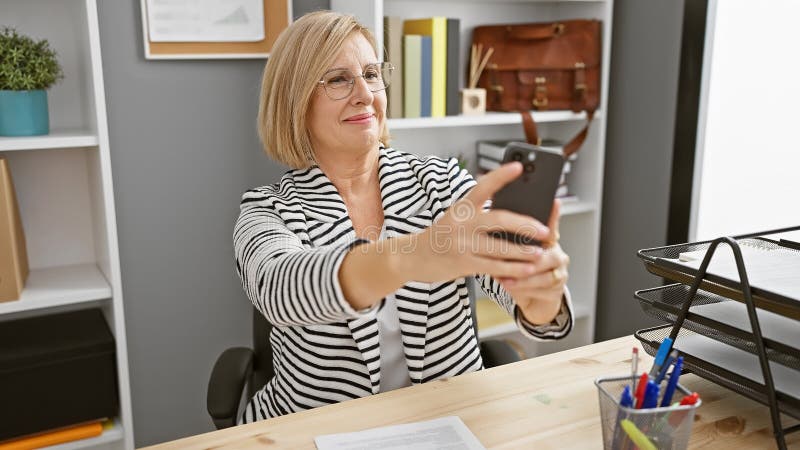 Smiling Mature Caucasian Woman Taking A Selfie In A Modern Office