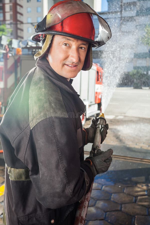 Smiling Mature Fireman Spraying Water during Stock Photo - Image of ...