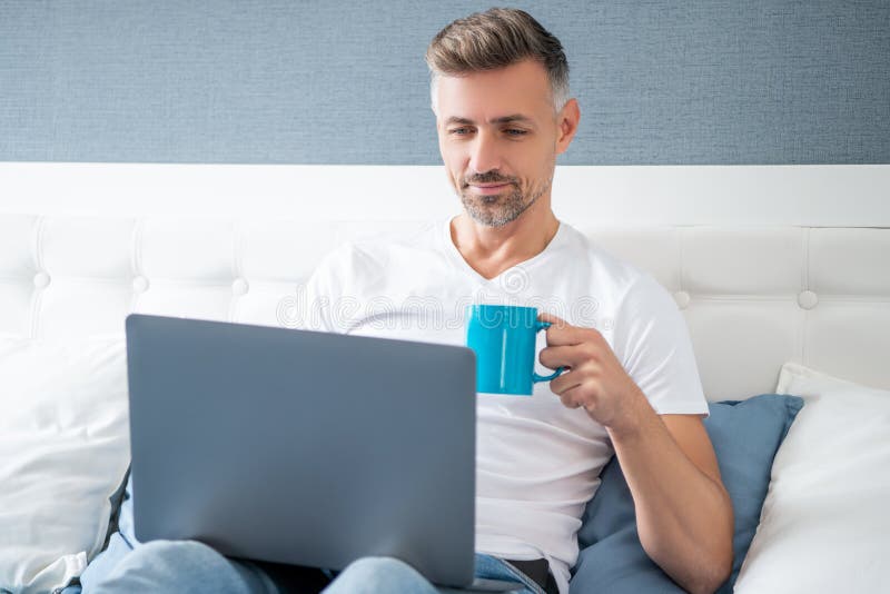 Smiling Mature Man Using Computer in Bed with Coffee Stock Photo ...