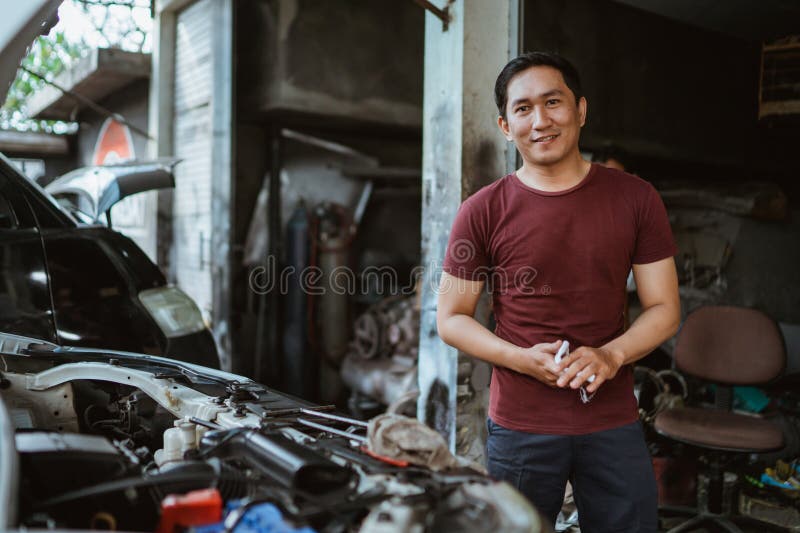 Smiling Mechanic Standing Up To Clean Hands with a Cloth after Working ...