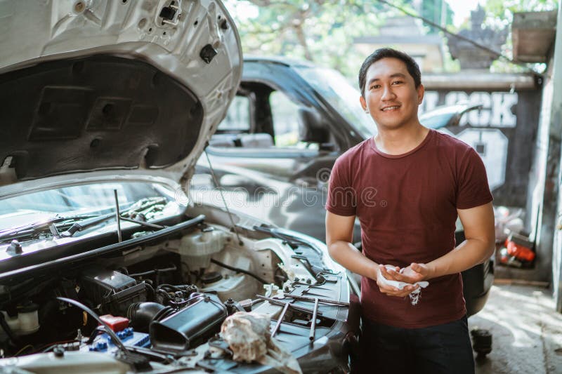 Smiling Mechanic Standing Up To Clean Hands with a Cloth after Working ...