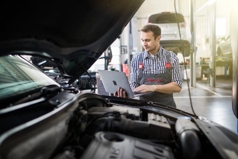 Smiling Young Man Mechanic Using a Laptop Computer To Check a Car ...