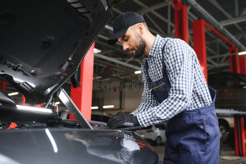 Smiling Mechanic Using a Laptop Pc at the Repair Garage. Stock Image ...