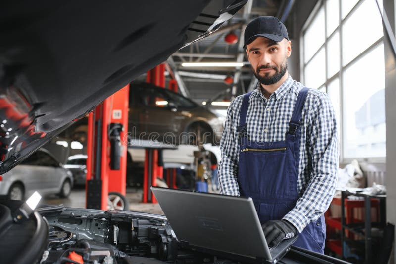 Smiling Mechanic Using a Laptop Pc at the Repair Garage. Stock Image ...
