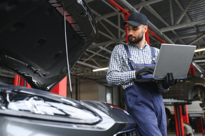 Smiling Mechanic Using a Laptop Pc at the Repair Garage. Stock Image ...