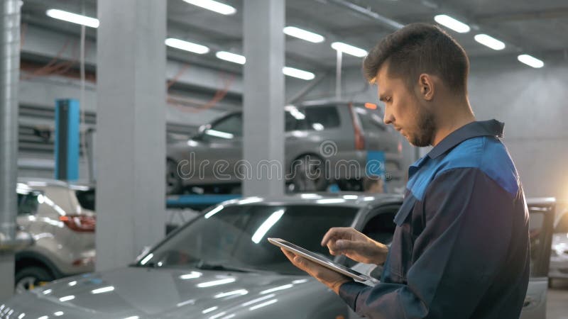 Smiling Mechanic Using a Tablet Pc at the Repair Garage Service Stock ...