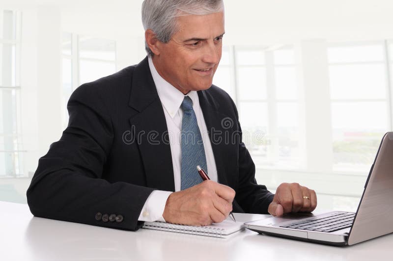 Smiling Middle Aged Businessman at Desk Using Laptop Computer and ...