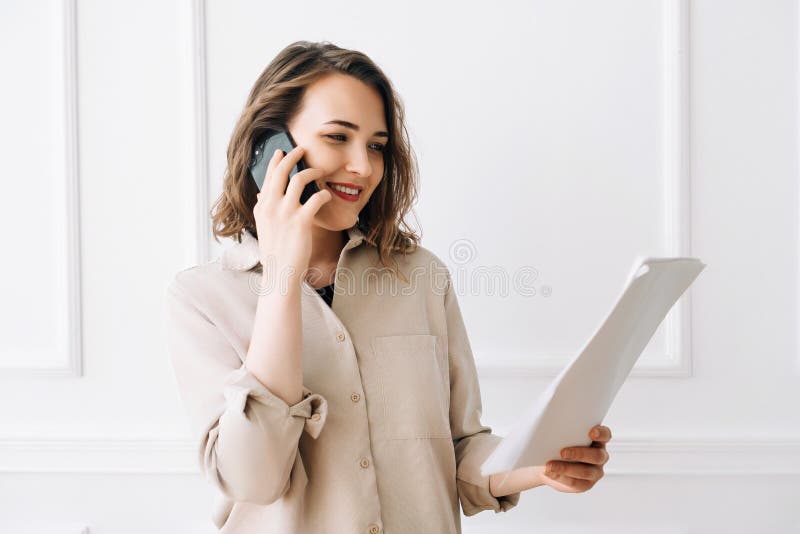 Smiling Millennial Woman Engaged in Phone Call, Discussing Documents ...