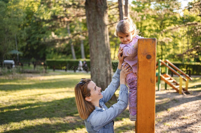 Smiling Mom Helps Her Cute Daughter Climb the Playground Stock Photo ...
