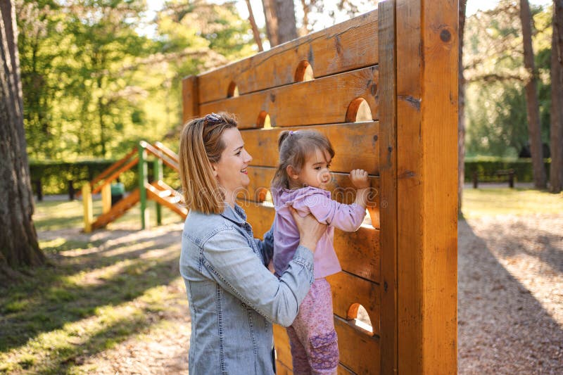 Smiling Mom Helps Her Cute Daughter Climb the Playground Stock Photo ...