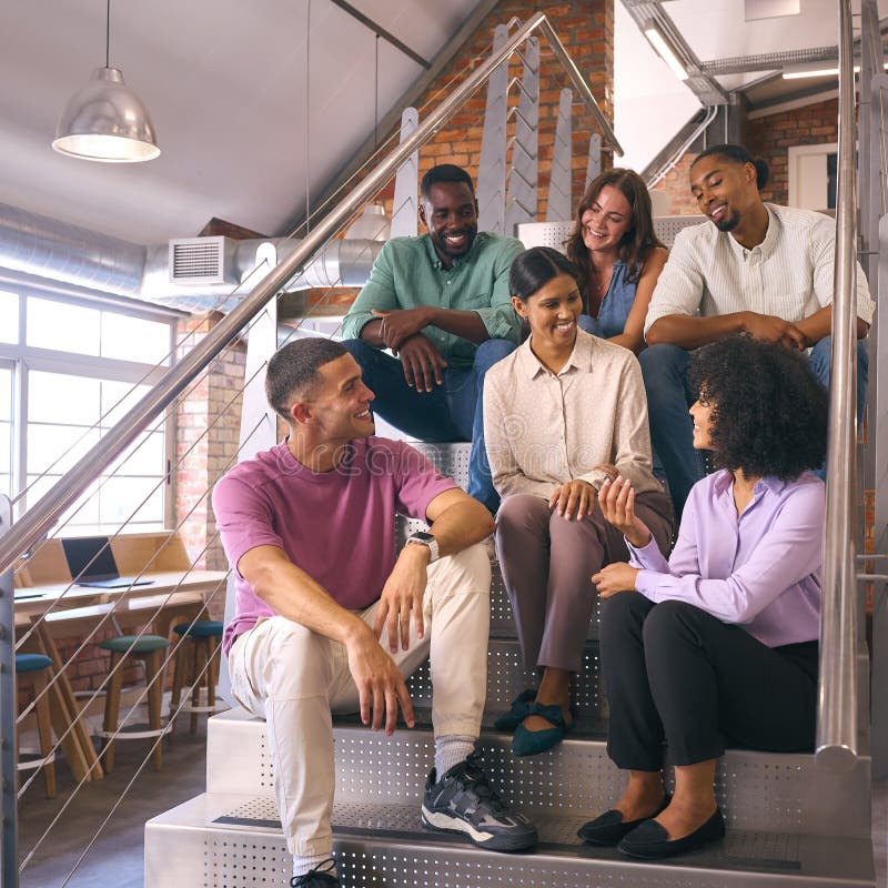 Smiling Multi-Cultural Business Team Sitting on Stairs in Modern Open ...