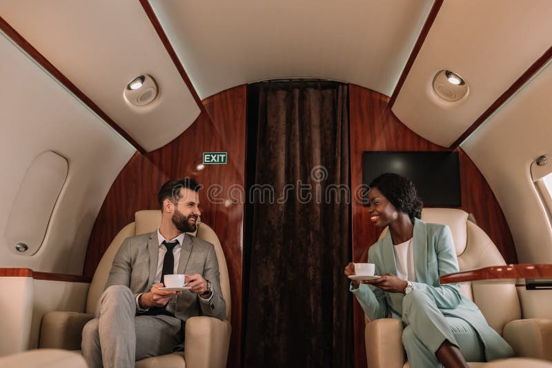 Smiling Multicultural Businesspeople Talking while Holding Cups of ... Smiling Multicultural Businesspeople Talking while Holding Cups of ...