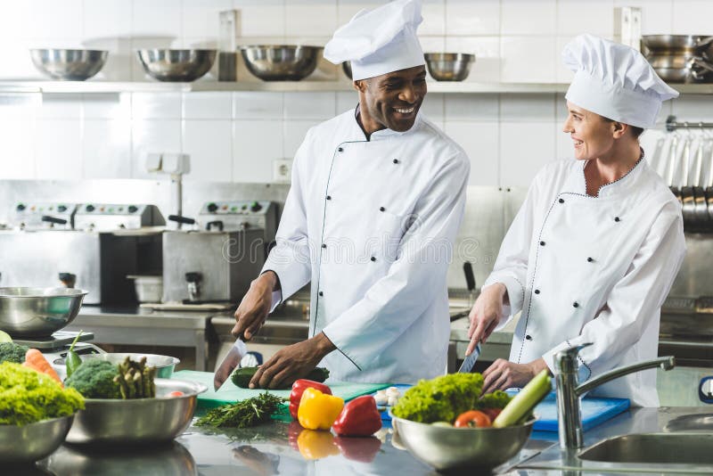 Smiling Multicultural Chefs Cutting Vegetables at Restaurant Kitchen ...