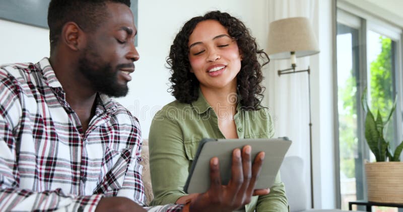 Smiling Multiracial Couple Using Tablet at Home, Enjoying Relaxed ...