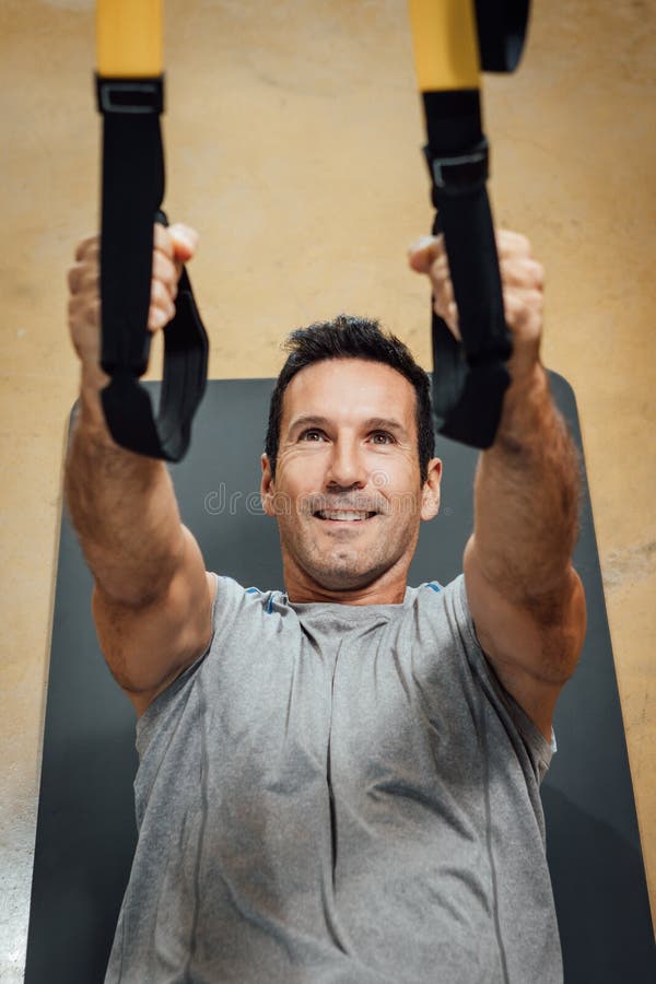 Smiling Muscular Man Performing Pull-up Exercise Using Suspension ...