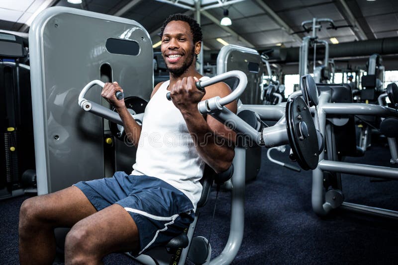 Smiling Muscular Man Using Exercise Machine Stock Image - Image of ...