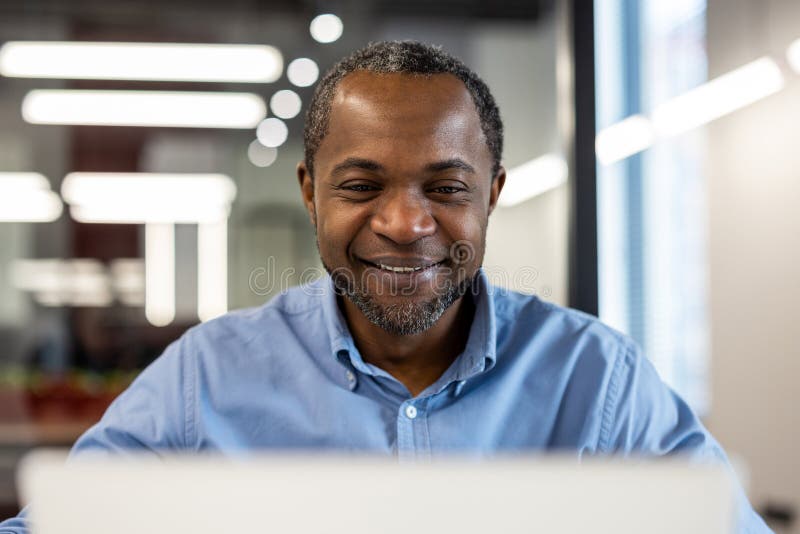 Smiling Office Worker in Blue Shirt Working on Laptop in Modern Office ...