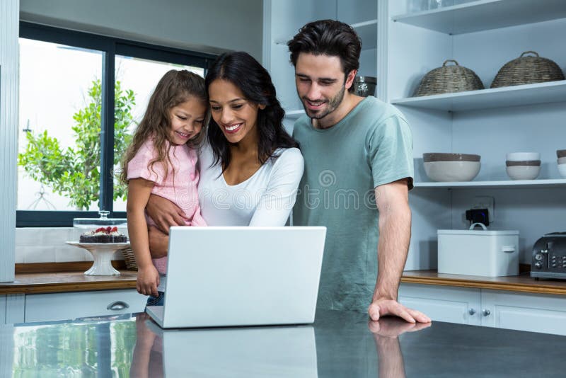 Smiling Parents Using Laptop with Daughter Stock Photo - Image of ...