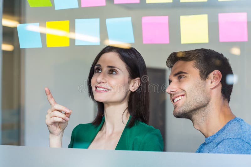 Smiling Partners Looking at Sticky Notes Stock Photo - Image of girl ...