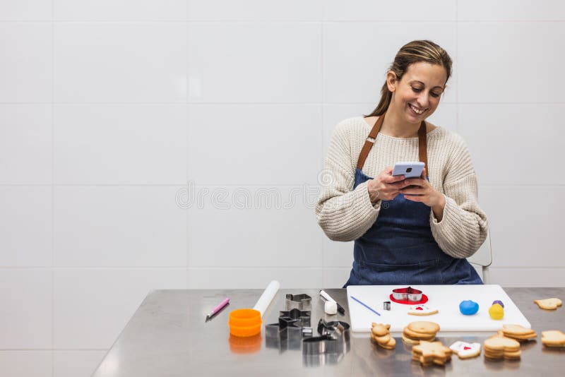 Smiling Pastry Chef Using Her Mobile Phone while Working in the Kitchen ...