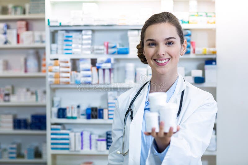 Smiling Pharmacist Showing Medicine Container in Pharmacy Stock Photo ...