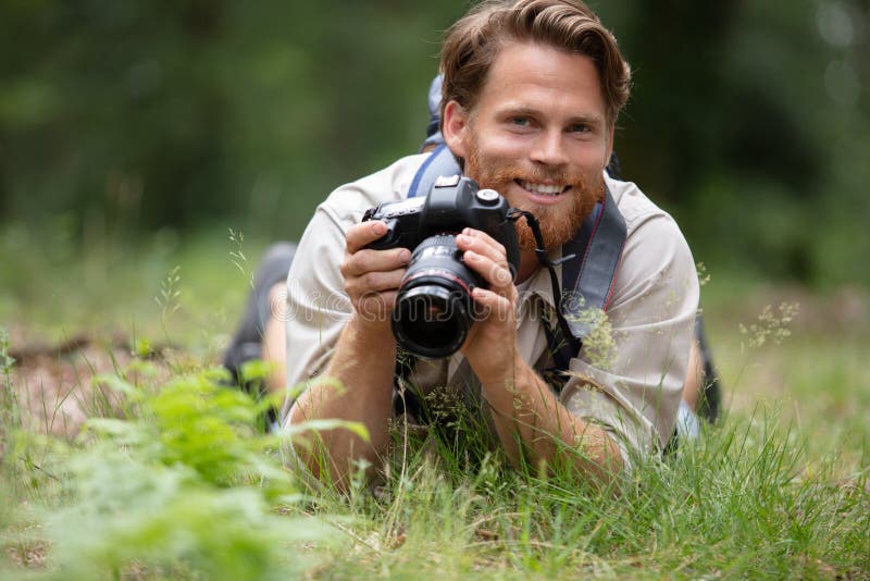Smiling Photographer Laying on Grass with Camera Stock Photo - Image of ...
