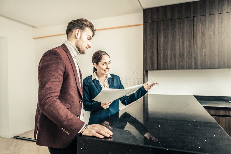 Smiling Pleasant Realtor Showing Her Client the Kitchen Stock Image ...