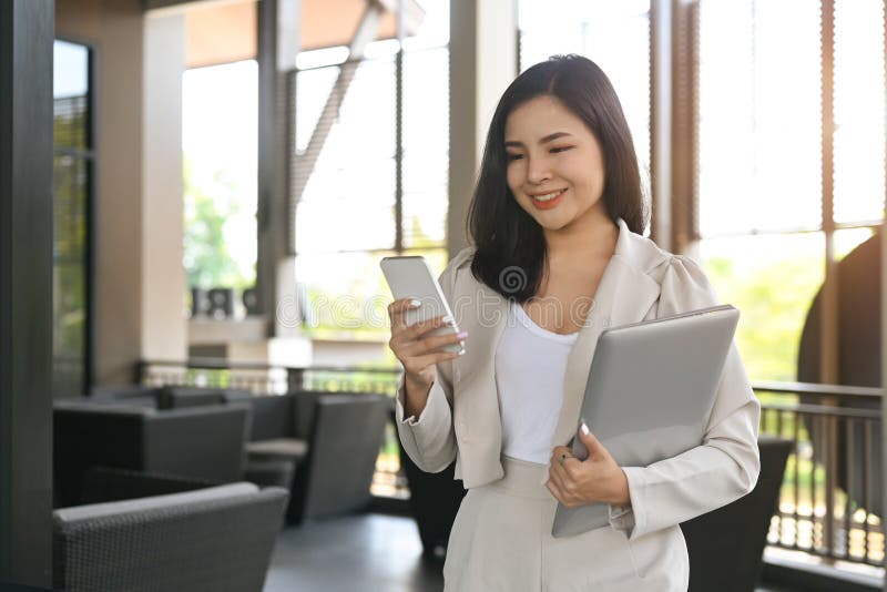 Professional Business Woman Using Mobile Phone while Standing in Modern ...