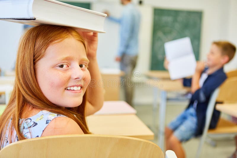 Smiling Redhead Student with Book on Head in Classroom Stock Photo ...