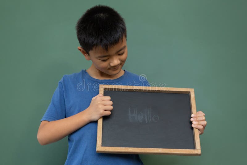 Smiling Schoolboy Standing and Holding a Hello Slate in a Classroom ...