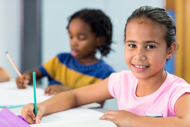 Smiling Schoolgirl with Classmate Writing on Book Stock Photo - Image ...
